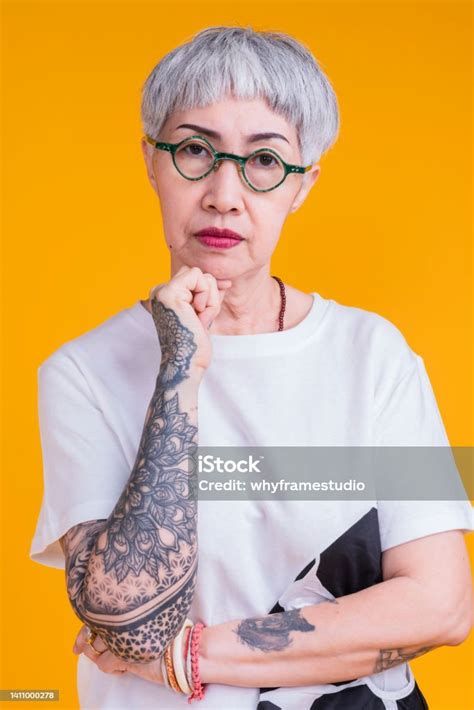 생각 포즈 아시아 시니어 여성은 안경 회색 머리를 캐주얼 천 손 문신 추상 패턴 초상화 헤드 샷에 노란색 배경에 착용 인물