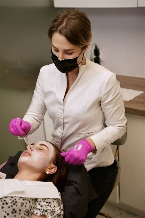 In A Beauty Salon A Cosmetologist In Pink Gloves Applies A Restorative