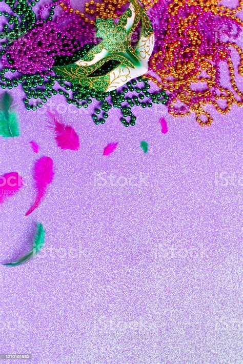 보라색과 녹색 카니발 마스크 깃털과 빛나는 구슬 전통적인 카니발 액세서리 보라색 배경에 마디 그라 프레임 또는 테두리 가면과 구슬 플랫 레이 복사 공간 상단보기 0명에 대한