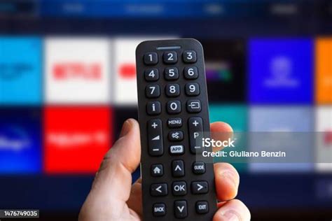 한 남자가 스마트 Tv의 리모컨을 손에 들고 있다 백그라운드에서 주문형 비디오용 스트리밍 엔터테인먼트 앱이 있는 Tv 화면을 볼