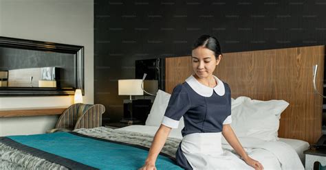 Young Pretty Maid In Uniform Sitting On Clean Blanket And Touching It