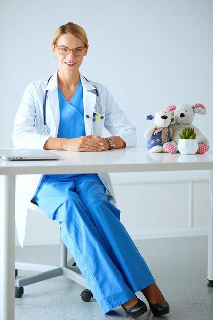 Doctora Sonriente Joven Hermosa Que Se Sienta En El Escritorio Foto Premium