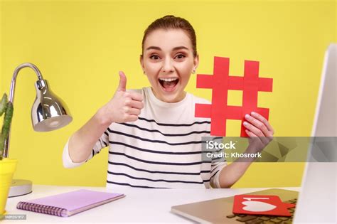 빨간 해시태그와 엄지손가락을 제스처처럼 올리고 셀카 Pov를 찍고 직장에 앉아 있는 여자 25 29세에 대한 스톡 사진 및 기타 이미지 Istock