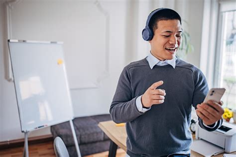 사무실에서 무선 헤드폰을 착용하고 스마트 폰으로 화상 통화를하는 비즈니스 Brand Name Smart Phone에 대한 스톡 사진 및 기타 이미지 Brand Name