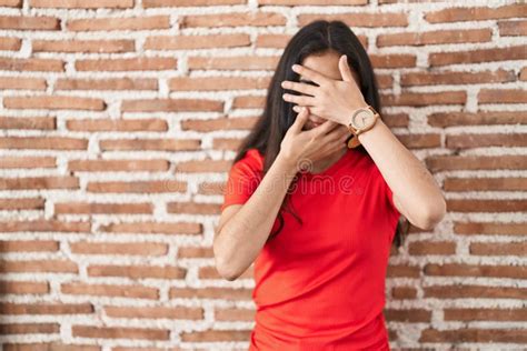 Young Teenager Girl Standing Over Bricks Wall Covering Eyes And Mouth