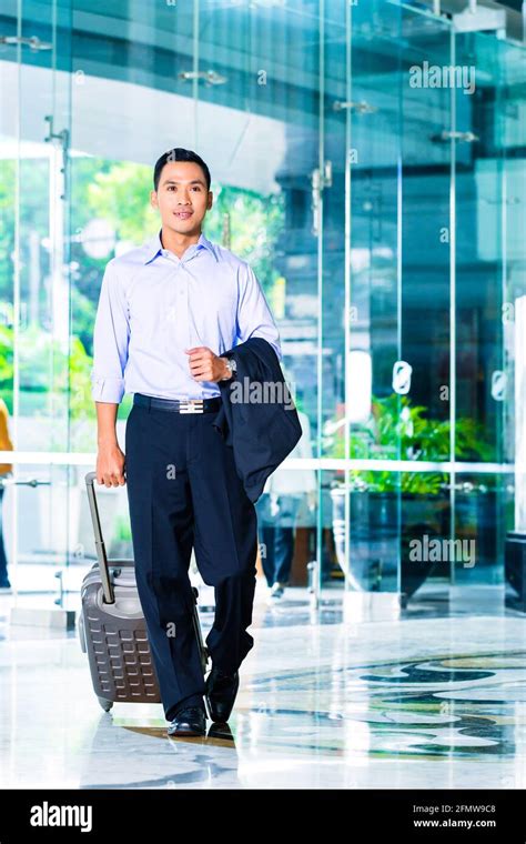 Asian Man Walking And Pulling Suitcase In Hotel Lobby Stock Photo Alamy