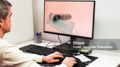 이미지 얼굴 마스크와 분홍색 배경에 고립 된 온도계의 종류와 컴퓨터 모니터를 사용하여 남자의 보기 코비드19 건강 개념