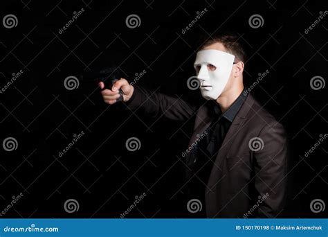A Man In A White Mask On A Black Background Threatens With A Gun Stock