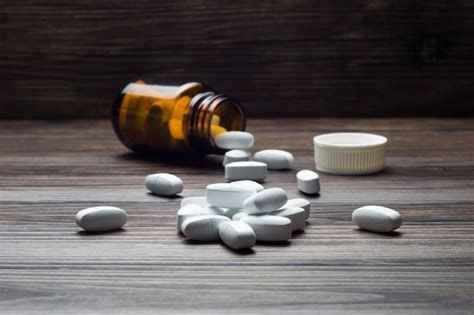 Premium Photo Medicine Pill Tablet With Spilled Bottle On Wooden Table