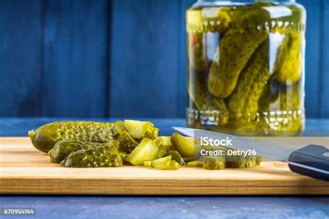 오이 또는 절인된 Gherkins 나무 절단 보드에 칼으로 블루 회색 배경입니다 오이와 은행입니다 가을에 대한 스톡 사진 및