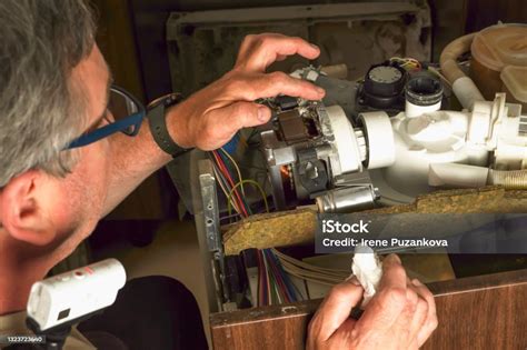 수리 서비스 작업자 성숙한 수리공 블로거가 오래된 식기 세척기 기계를 열고 있습니다 수리 서비스 개념 식기 세척기 기계 수리 과정 금속 부품의 배율 전기 모터에 대한 스톡