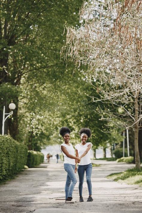 Hermanas Gemelas Cogidas De La Mano Y Caminando Por Un Parque Imagen De