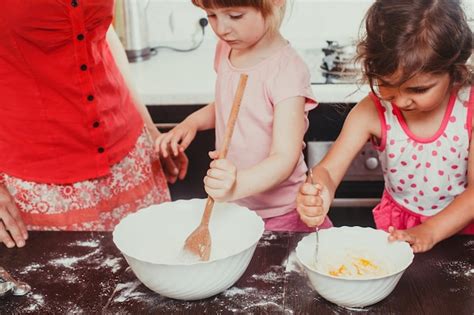 Mamá está horneando galletas con sus hijos en la cocina de casa Foto Premium