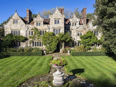A Large House With Many Windows And Lots Of Greenery On The Front Lawn