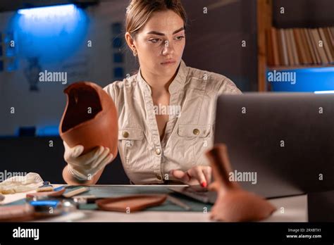 Female Archaeologist Doing Research Working Late Night In Office Using