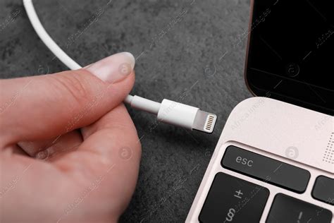 Woman Plugging Usb Cable With Lightning Connector Into Laptop Port On Dark Table Closeup Stock