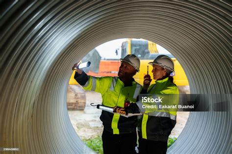 남녀 엔지니어가 대형 강관 내부를 검사합니다 작업자들은 산업 플랜트에서 석유 천연 가스 및 연료를 운송하기 위한 파이프라인을