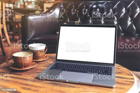 空白のデスクトップ画面とカフェで木製テーブルの上のコーヒー カップとノート パソコンのモックアップ画像 からっぽのストックフォトや画像を