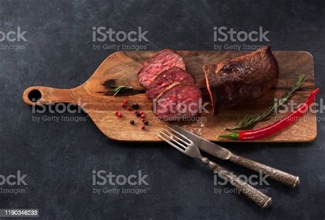 로즈마리와 칠리 페퍼를 곁들인 나무 판에 구운 쇠고기 콘크리트 검은 색 배경 최고 전망 고기에 대한 스톡 사진 및 기타 이미지