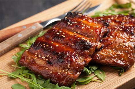 돼지 갈비 바베 큐 소스 구이 Arugula의 침대에 꿀에 Caramelized 어두운 콘크리트 바탕에 신청 위한 나무 보드에