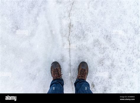 Male Feet Stand On A Snowy Ice With Crack First Person View Top View