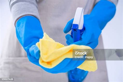 젊은 여성 가정부는 파란색 장갑 스프레이 클리너 젖은 노란색 헝겊으로 앞치마에 흰색 테이블을 청소하고 있습니다 가구에 대한 스톡 사진 및 기타 이미지 Istock