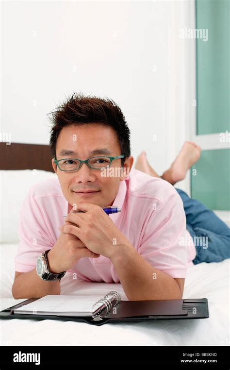 Man Lying On Bed Hand On Chin Notebook Open In Front Of Him Stock
