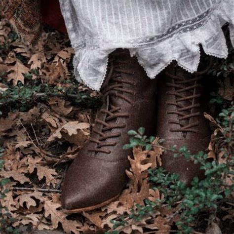 A Pair Of Brown Shoes Sitting On Top Of Leaves