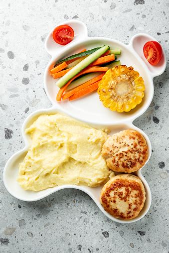 장난기 넘치는 어린이용 접시에는 크리미한 으깬 감자 황금빛 옥수수 채소 스틱 바삭한 패티 2개가 포함되어 있어 매력적인 식사 프레젠테이션에 이상적입니다 감자 요리에 대한