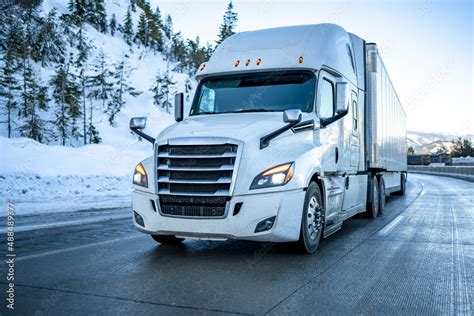 Bonnet Big Rig White Semi Truck With Turned On Headlights Transporting