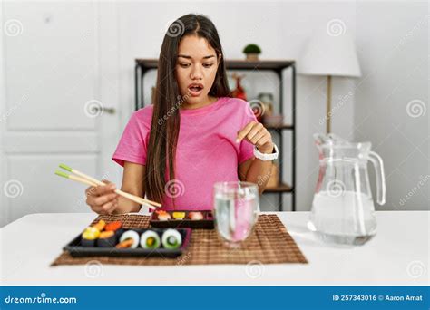 Young Brunette Woman Eating Sushi Using Chopsticks Pointing Down With