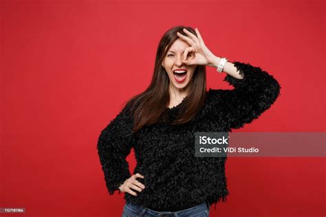 재미 있는 젊은 여자 눈 근처 손을 잡고 모피 스웨터에 확인을 보여주는 안경이 나 쌍안경 모방에 고립 된 빨간 배경 몸짓 사람들이 진심으 감정 라이프 스타일 개념 복사