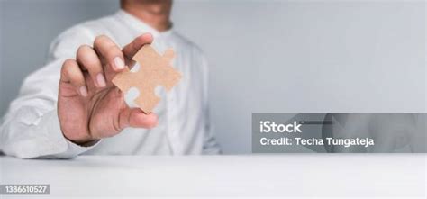 사업가의 손에 하나의 직소 퍼즐 요소 사람의 손은 복사 공간이있는 테이블에 중요한 직소 퍼즐의 조각을 보여주고 흰색 배경 비즈니스 솔루션 및 아이디어 개념 개념에 대한 스톡