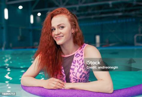 80 년대 의 스타일에 유행 수영복에 아름다운 젊은 빨간 머리 소녀는 실내 수영장에서 그녀의 손에 국수와 함께 서 건강관리와