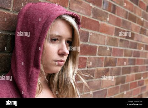 Sulky Blonde Teenage Girl Wearing A Hoodie Leaning Against A Wall