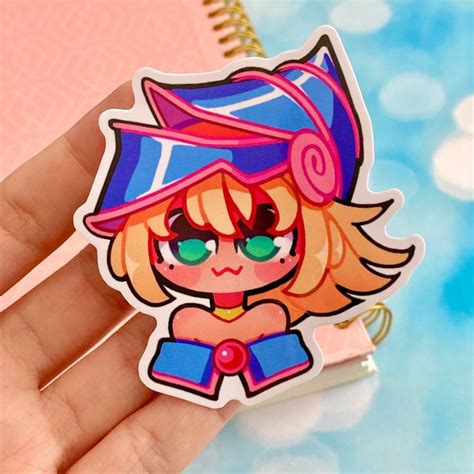 A Hand Holding A Small Sticker With A Cartoon Character On It S Face