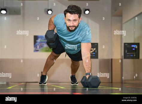 Athletic Man Performing A Plank Row With Dumbbells In A Gym