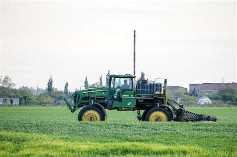 미세 하 게 분산 된 비료 살포 장치 트랙터 일몰 배경에 트랙터입니다 높은 바퀴 트랙터 젊은 밀에 비료를 만들고 있다 미세 하 게 분산 된 스프레이 화학 물질의 사용