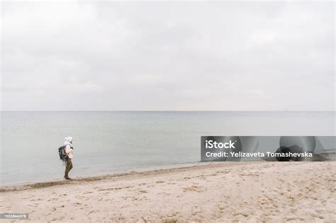 겨울에 발트 해 근처의 모래 해변에 검은 배낭을 가진 백인 남자 젊은 백인 여자 관광 한 사람 혼자 테마 여행 수평선을 내려다