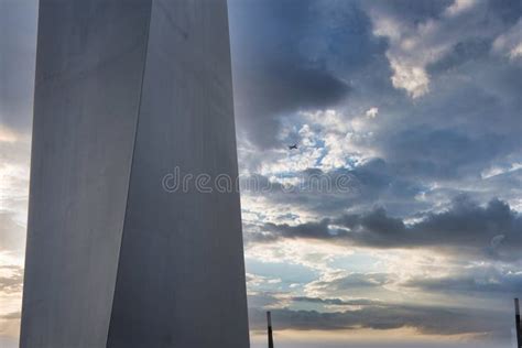 modern angular structure with airplane and partly cloudy sky stock