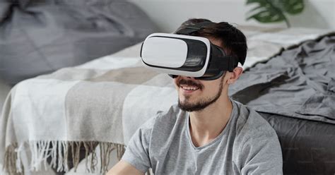 쾌활한 젊은 수염 난 남자가 카펫 위에 다리를 꼬고 앉아 검역소에서 가상 현실 고글을 사용하여 비디오 게임을 하고 있다 사진 Unsplash의 한 사람 이미지