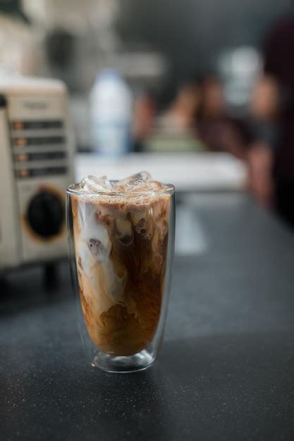 Premium Photo Ice Coffee On A Table With Cream Being Poured Into It