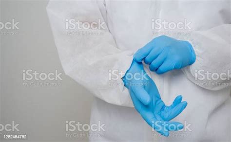흰색 배경에 고립 된 그의 손에 파란색 장갑을 검사 Ppe 정장에 넣어 바이러스 학자의 초상화를 닫습니다 개인 보호 장비 개념