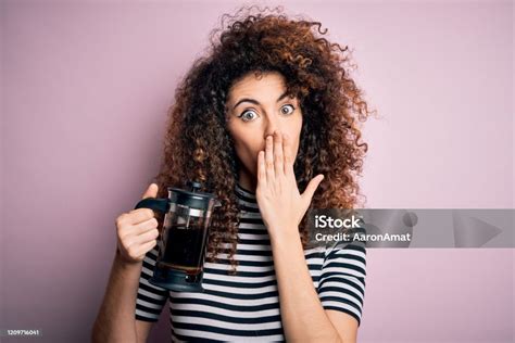 곱슬 머리와 피어싱 커피를 들고 커피를 하고 있는 젊은 아름다운 여자는 실수 두려움의 표정 침묵 비밀 개념에 대한 수치심으로