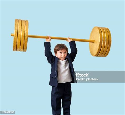 파란색 파스텔 배경에 귀여운 아이 리프팅 골드 바벨입니다 그는 단호하고 성공적인 아이입니다 2 3 살에 대한 스톡 사진 및 기타