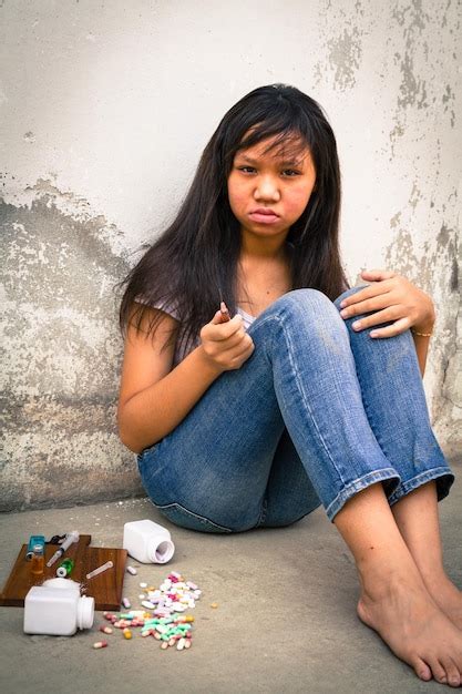 Premium Photo Sad Teenage Girl With Drugs Sitting On Floor Against Wall