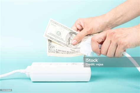 파란색 배경에 파워 스트립 연장 코드 근처의 전력 플러그와 미국 달러 지폐를 들고있는 여성 손 전기 비용 전기 가격 인상 값