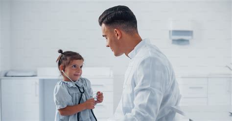 소녀에게 청진기 사용법을 가르칩니다 젊은 소아과 의사는 클리닉에서 작은 여성 방문객과 함께 일합니다 사진 Unsplash의 건강 검진 이미지