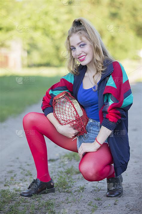 一位美丽的90年代乡村女孩穿着鲜艳的衣服，拿着一个装着桦树汁的网袋。