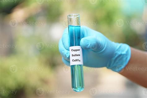 Close Up Hand Wear Blue Glove Holds Test Tube Of Copper Sulfate Liquid